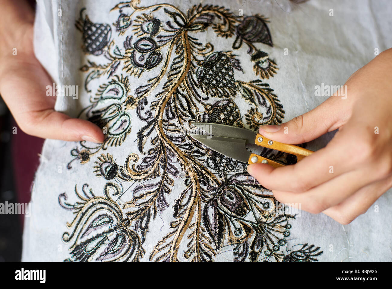 Close-up of woman worker hands cutting away short loose ends of threads ...