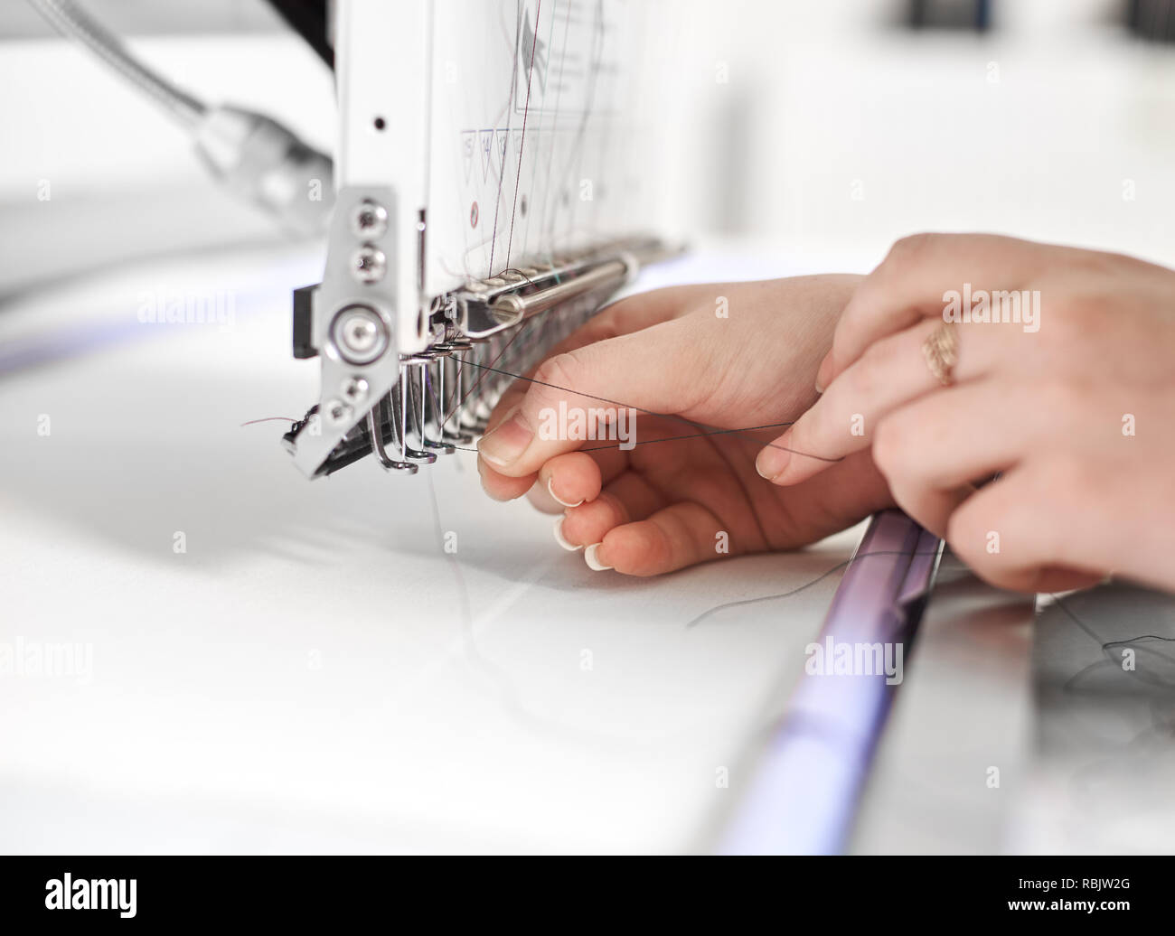 Close-up of woman hands filling thread in modern embroidery machine on ...