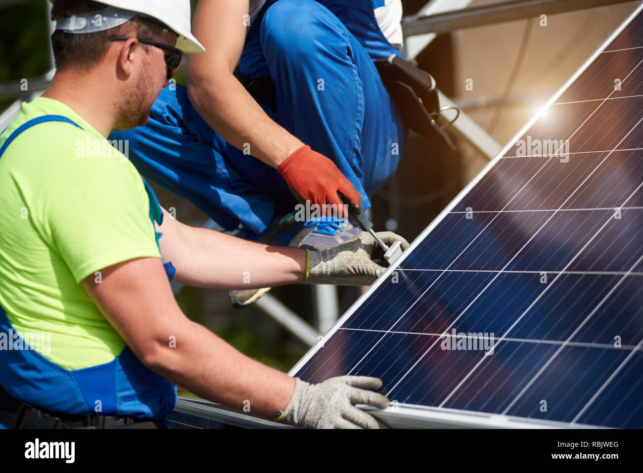Two professional technicians connecting solar photo voltaic panel to ...
