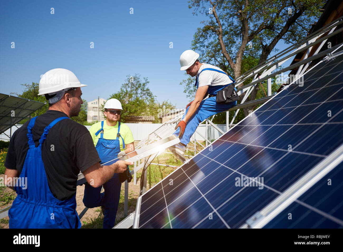 Team of three professional workers lifting heavy solar photo voltaic ...