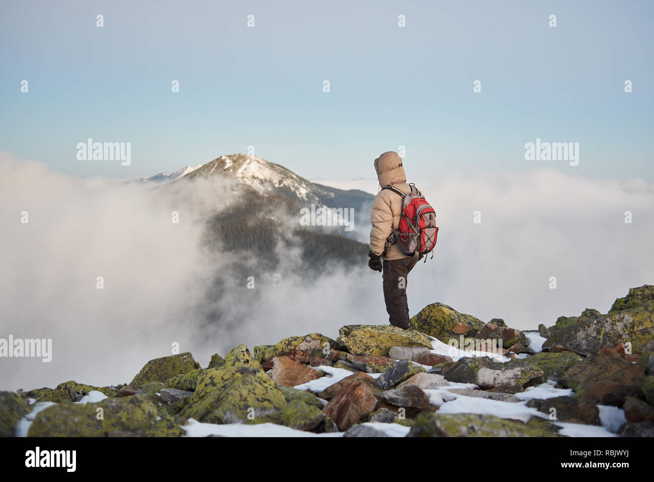 Back view of tourist traveler in warm clothing with backpack on the top ...