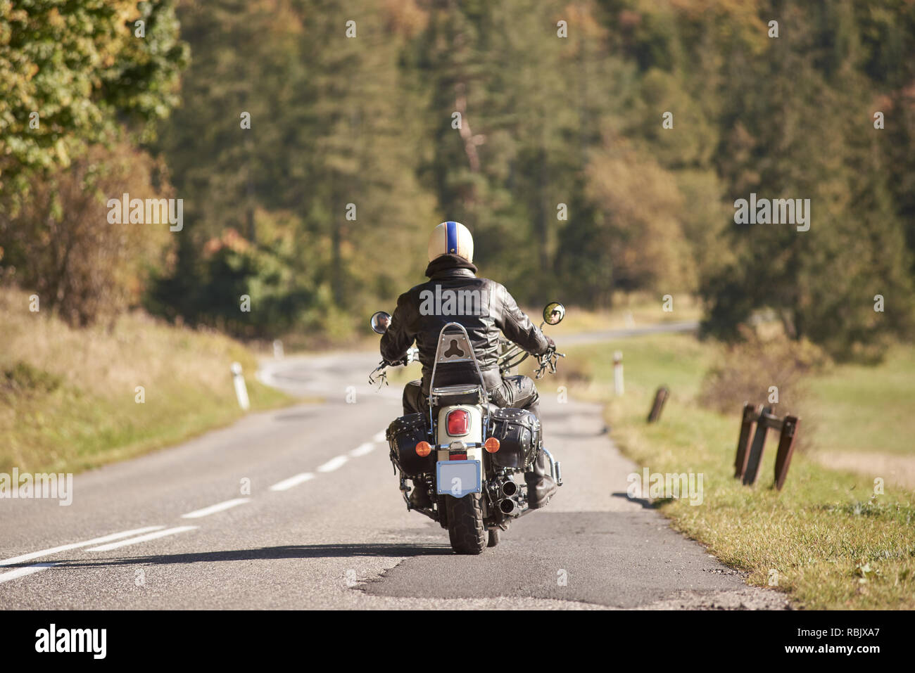 Back view of biker in black leather jacket and helmet riding motorcycle ...