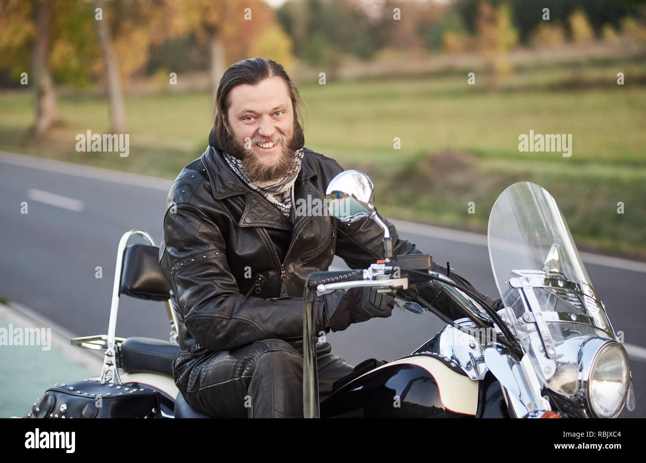 Portrait of bearded happy smiling motorcyclist in black leather ...