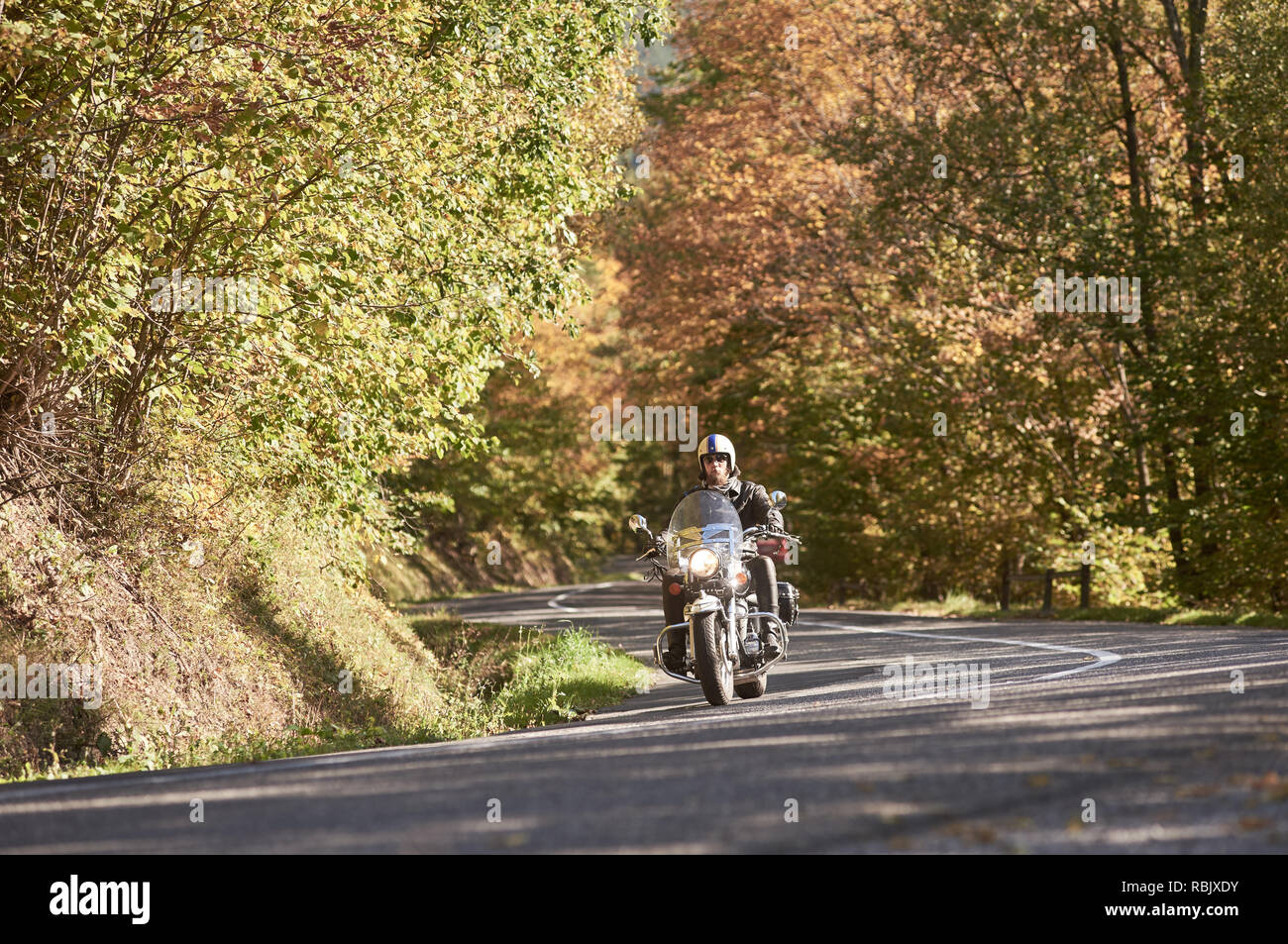 Bearded motorcyclist in helmet, sunglasses and black leather clothing ...