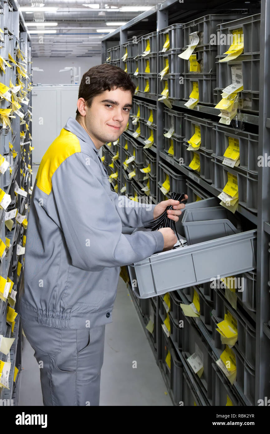 Worker in warehouse among long shelves with a variety of boxes Stock ...