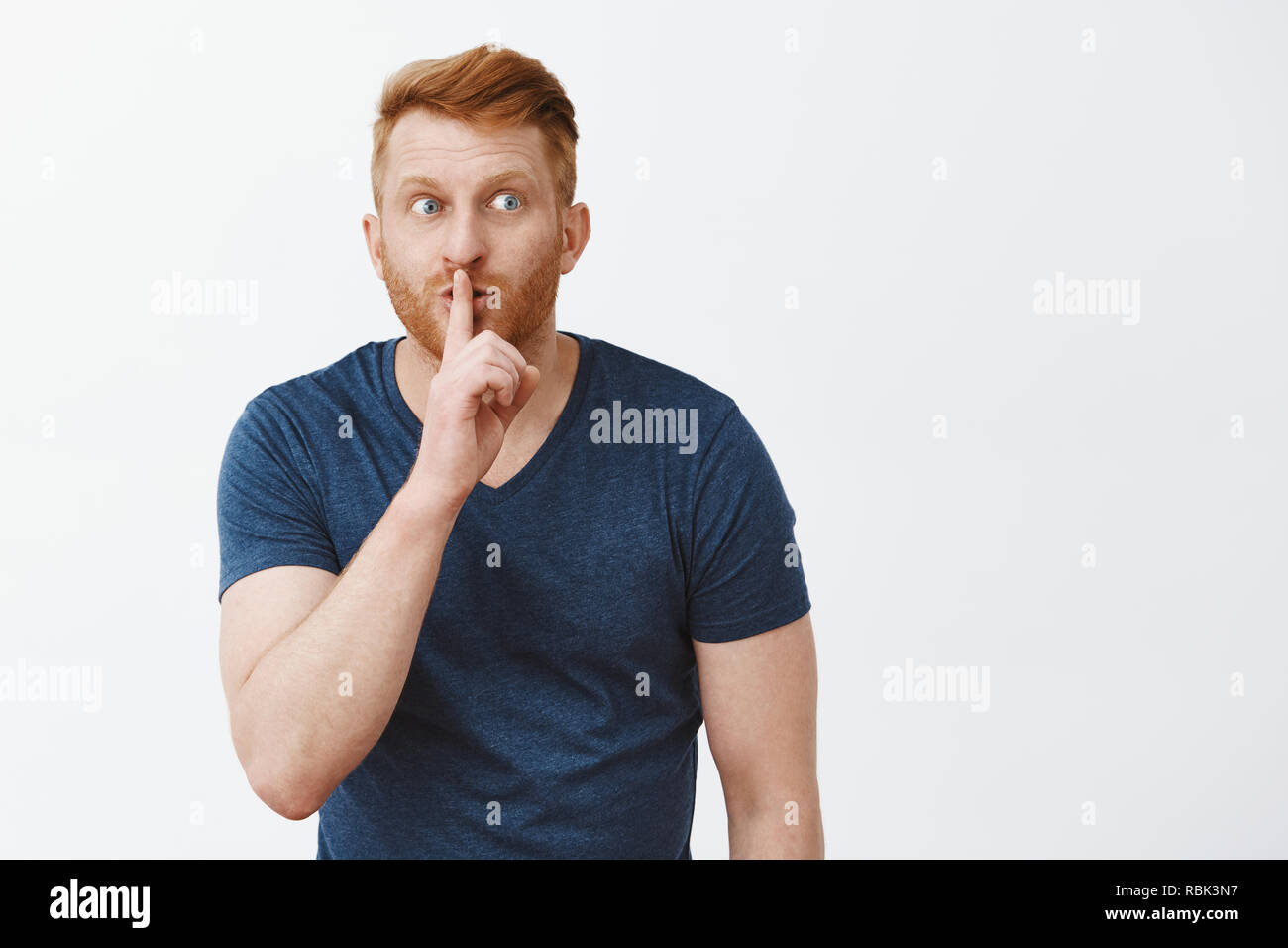 Attractive nervous redhead guy with beard, bending towards camera ...
