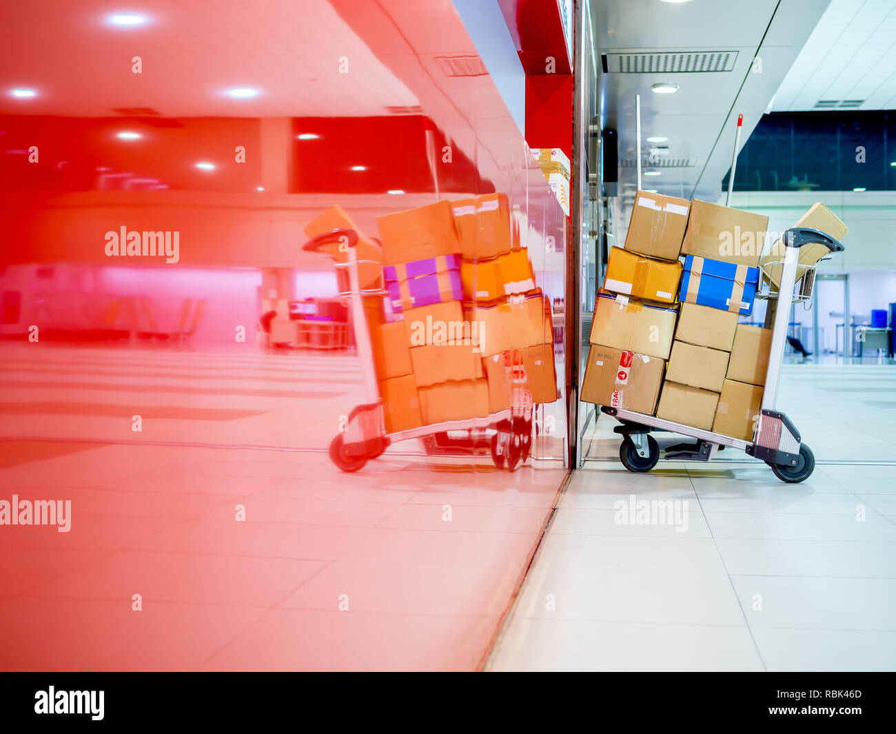 Lots of cardboards boxes on airport luggage cart near the red wall in ...