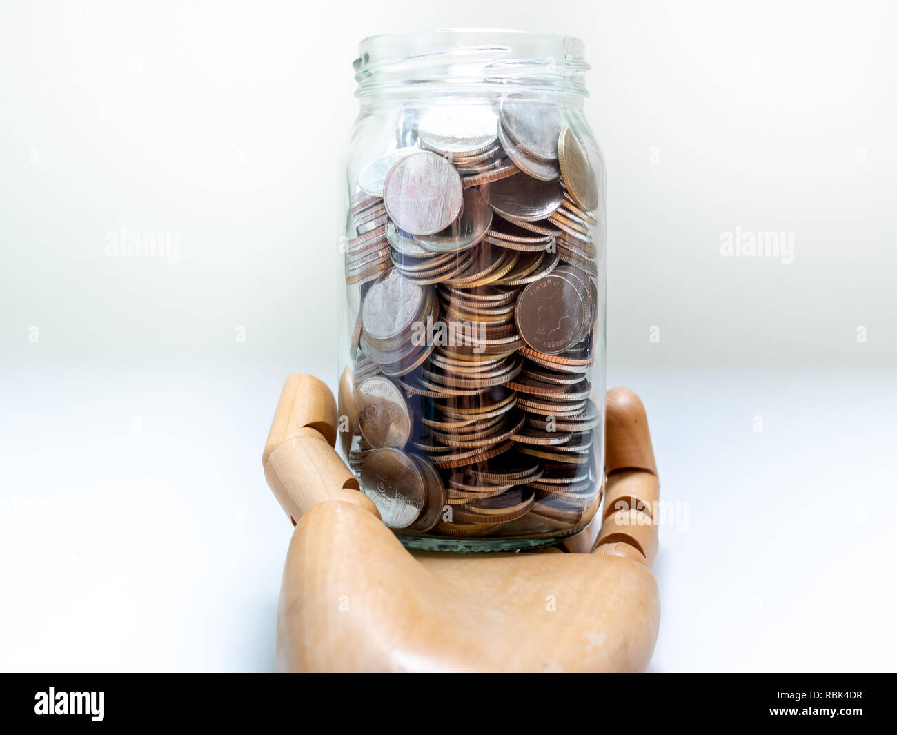 Wooden hand holding coins in glass jar isolated on white background ...