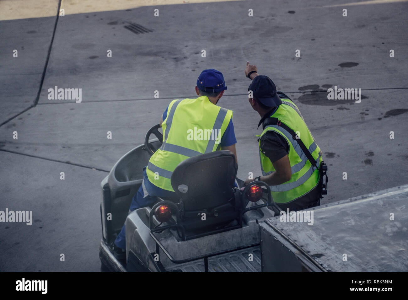Airport employees coordinating container transport for loading an ...