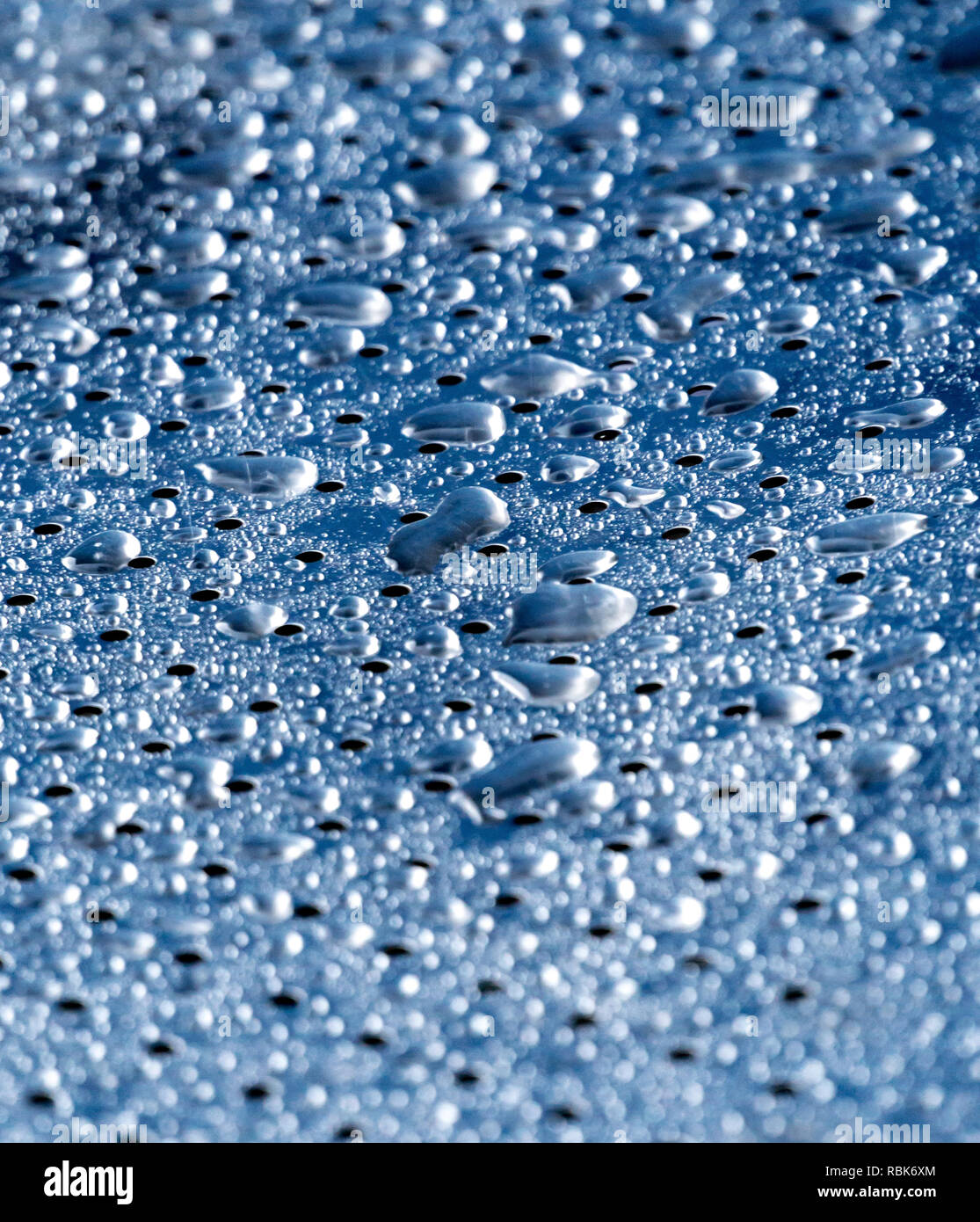 Closeup of water drops on a metal surface with holes in it Stock Photo ...