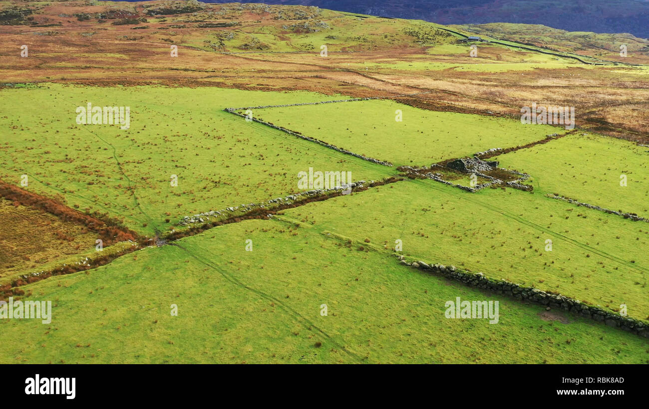 Overhead aerial view of green fields with old stone house ruin in North ...