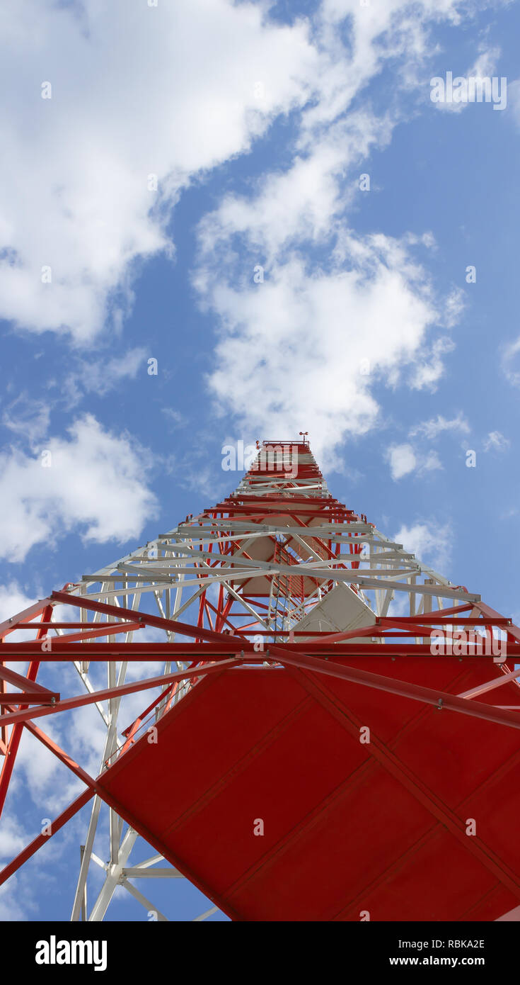 A red white telecommunications tower with a blue sky and white clouds Stock Photo - Alamy