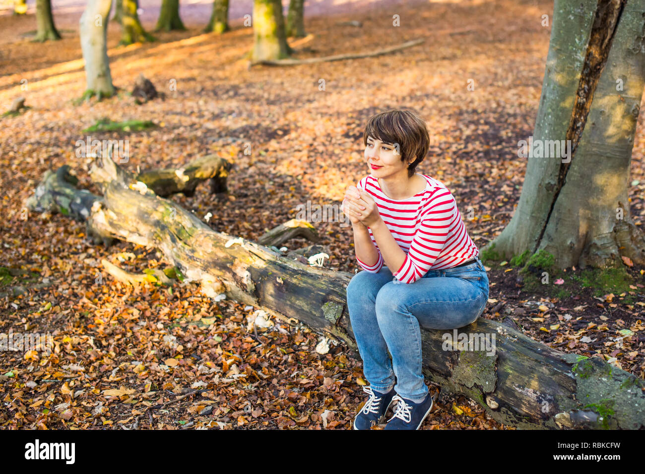 Woman sitting smiling on fallen tree hi-res stock photography and ...