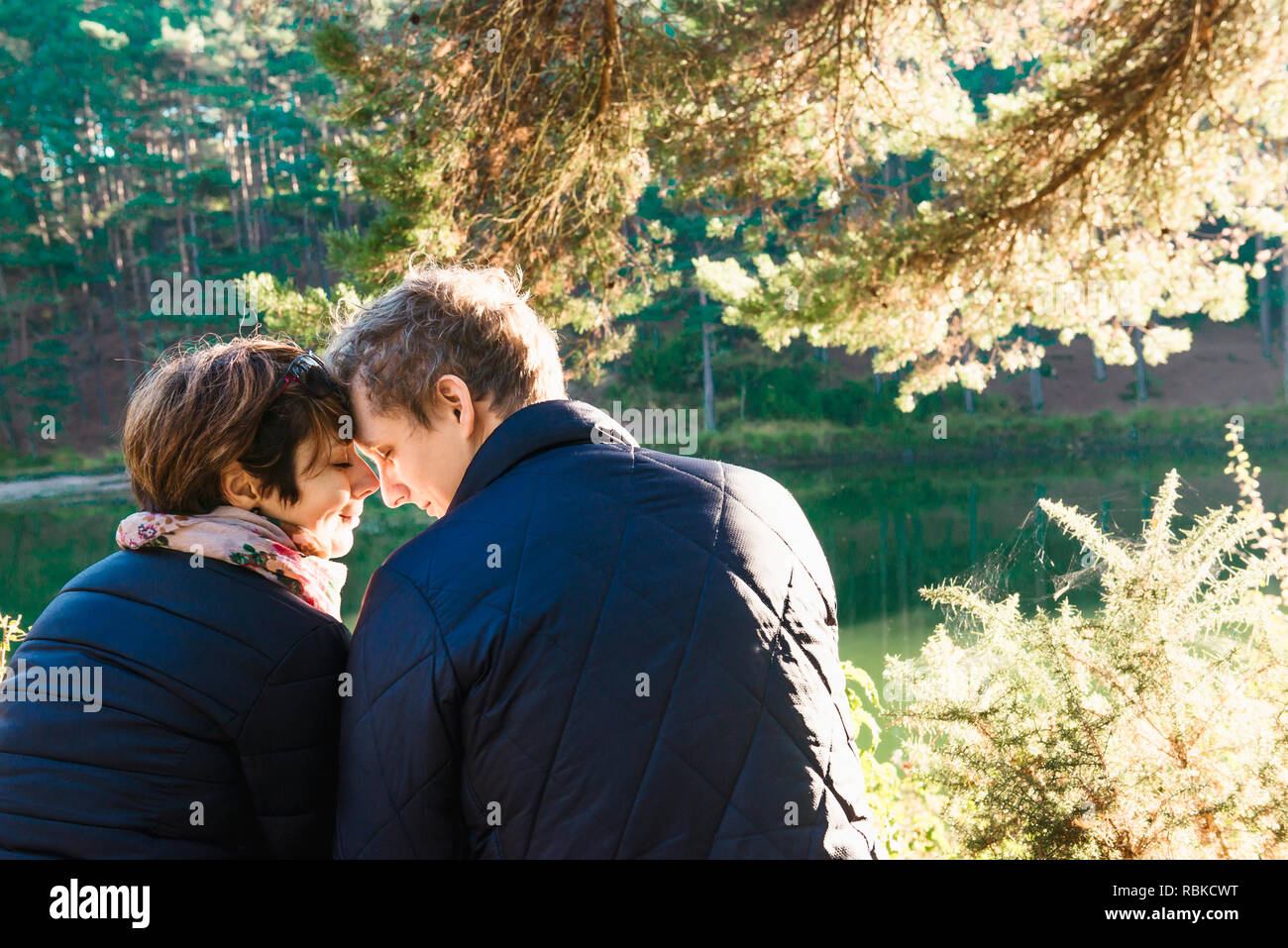 Back view of lovely couple man and woman sitting near river or lake ...