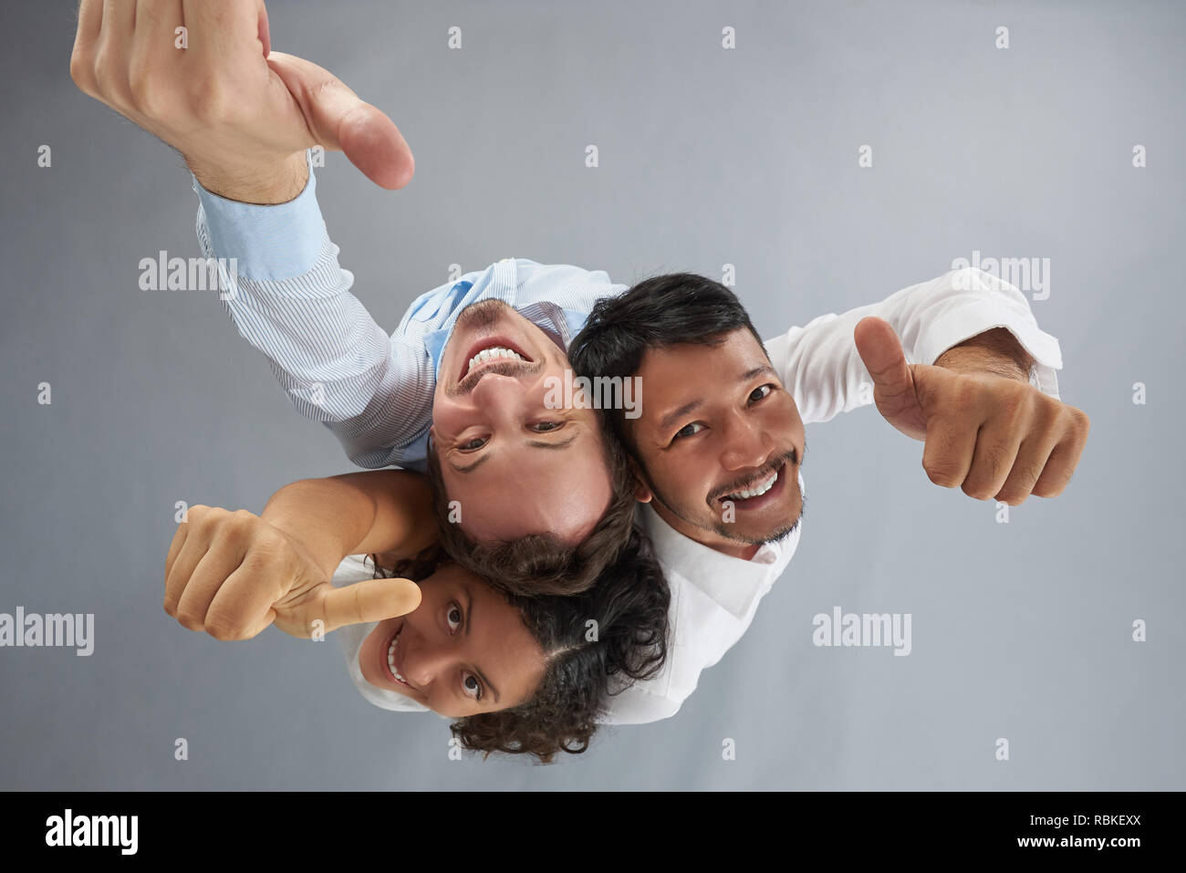 Group of smiling people showing thumb up above top view on gray studio ...