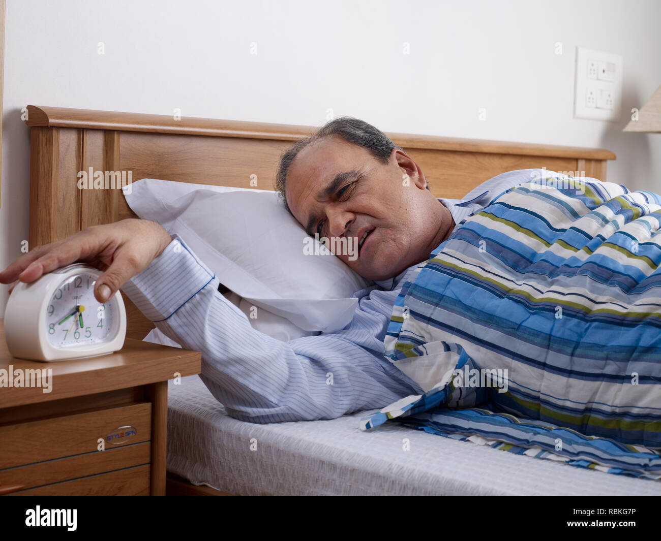 OLD MAN SWITCHING OFF AN ALARM CLOCK WHILE STILL SPEEPING Stock Photo ...