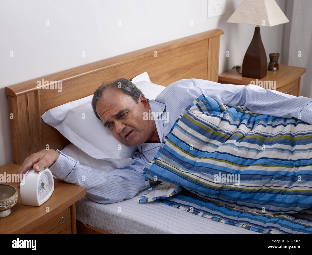 OLD MAN SWITCHING OFF AN ALARM CLOCK WHILE STILL SPEEPING Stock Photo ...