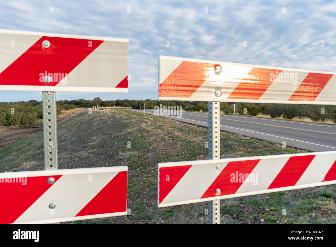 View of Curve and traffic signs past road block Stock Photo - Alamy