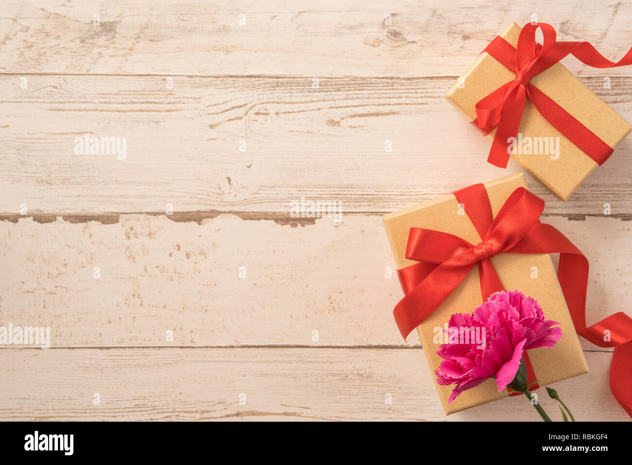 Kraft gift box with red ribbon bow and carnation, concept of giving ...