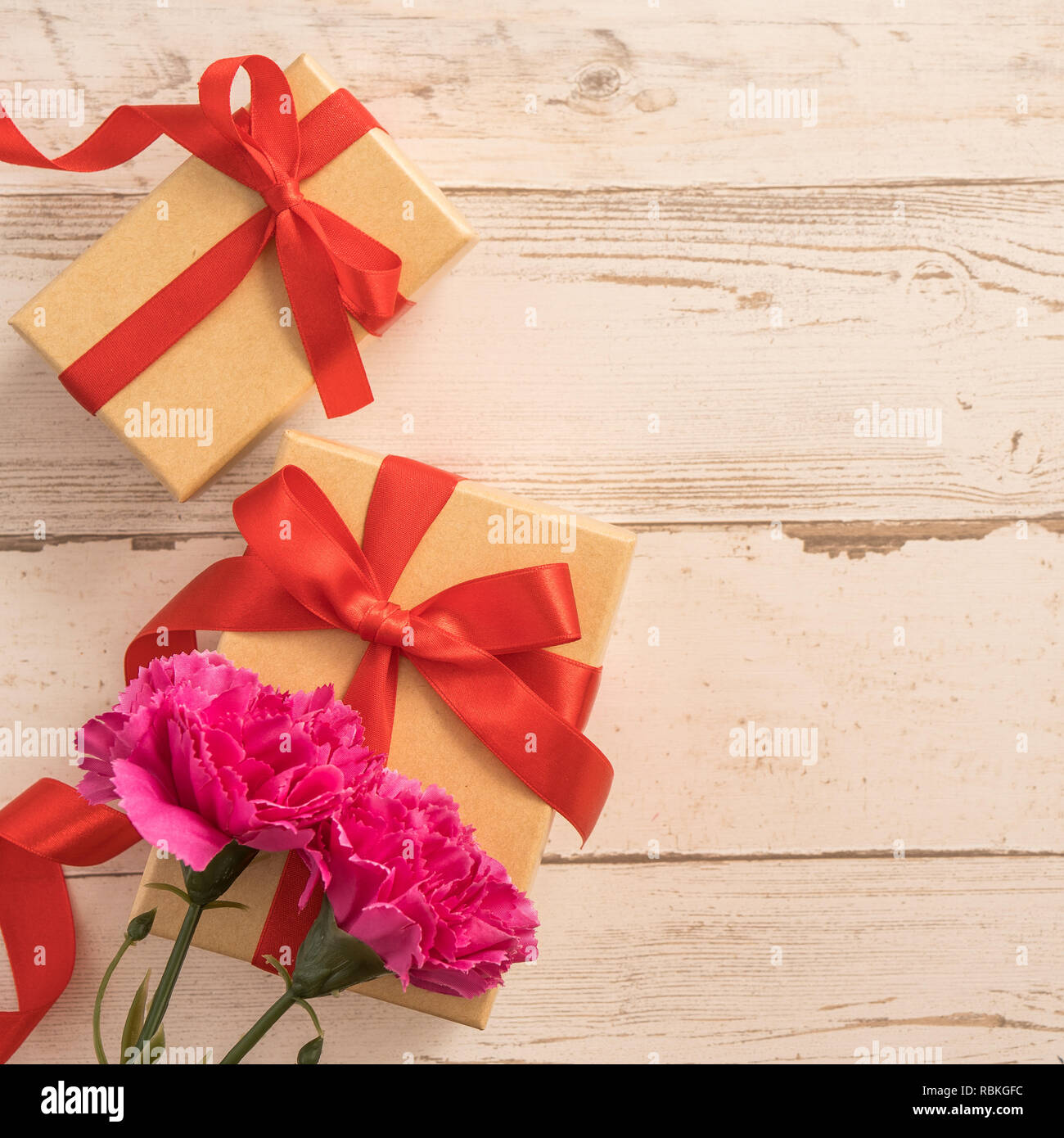 Kraft gift box with red ribbon bow and carnation, concept of giving ...