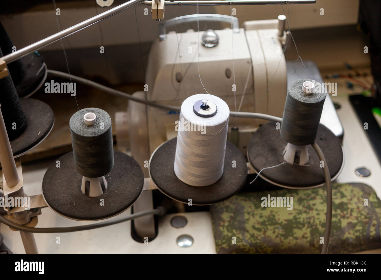 Three big black and white bobbins with large mating threads mounted on ...
