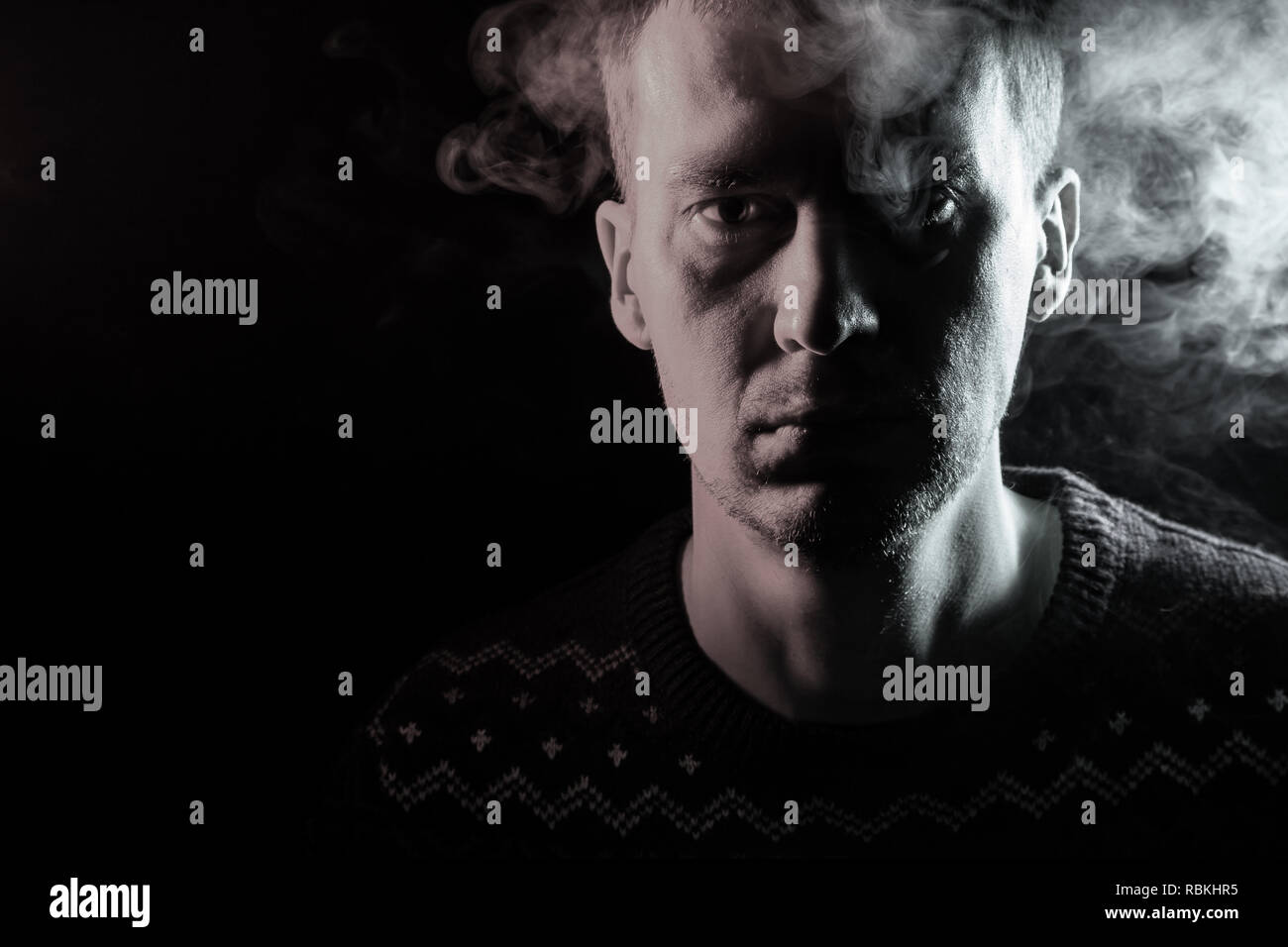 Portrait of a short-haired guy with a shadow on a serious face wearing ...