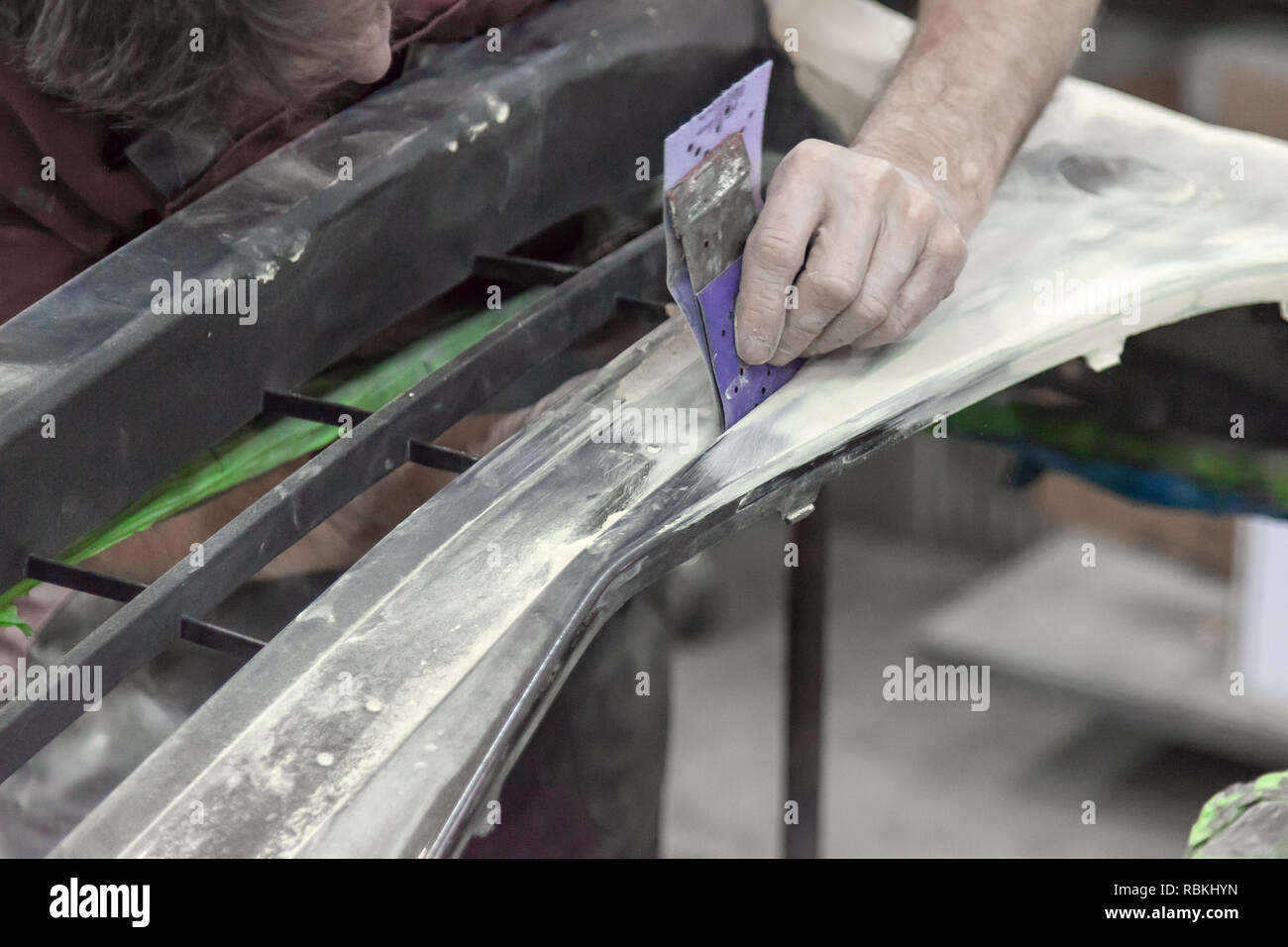A man prepares a car body element for painting after an accident with ...