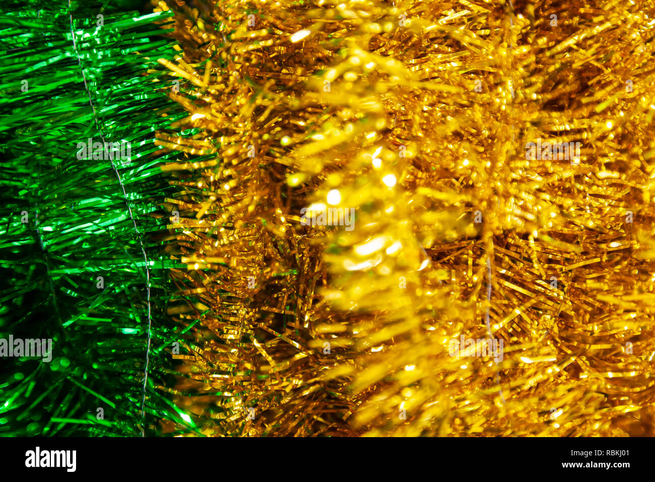 Close-up on shiny yellow and green tinsel hanging vertically in ...