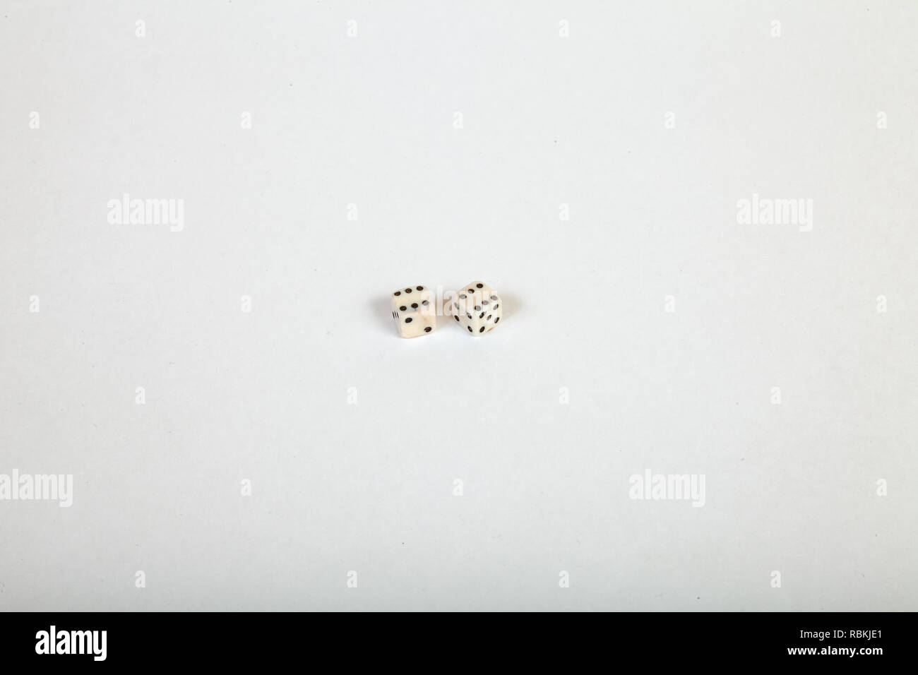 Two very small dice near each other on a large white isolated ...
