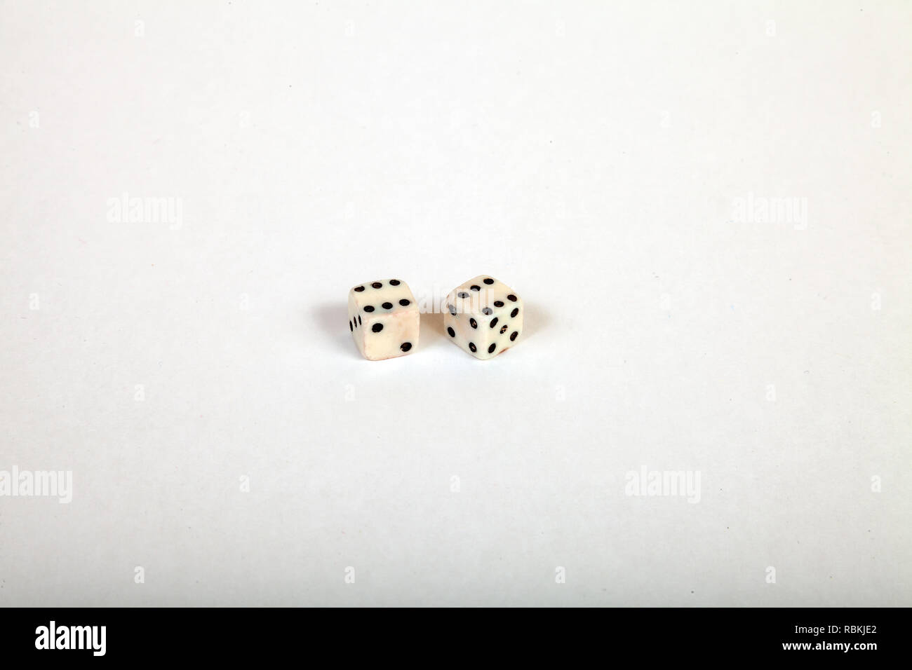 Two very small dice near each other on a large white isolated ...