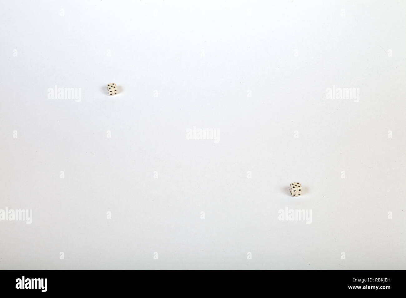 Two very small dice on the sides of a large white isolated background ...