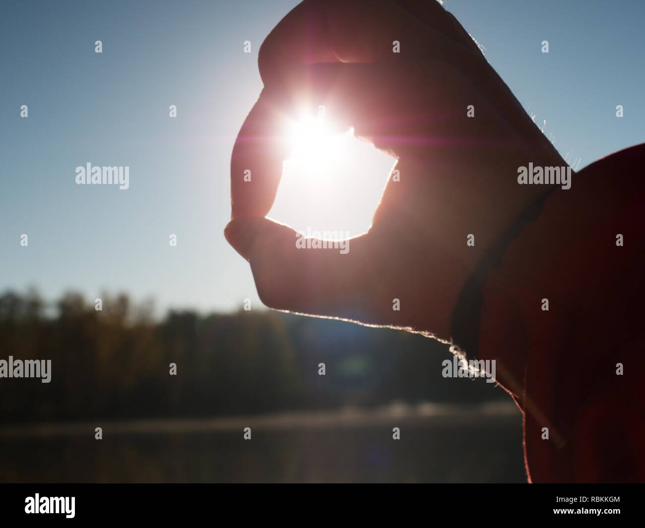 Hands catch sun at sunset time. Female fingers hold sun above lake ...