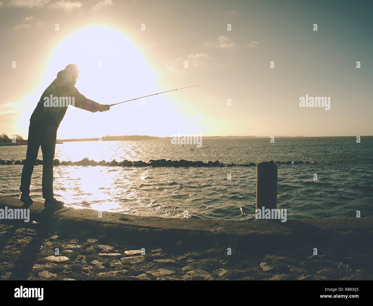 Fisherman with hat on the sea mole with fish rod. Man standing above ...