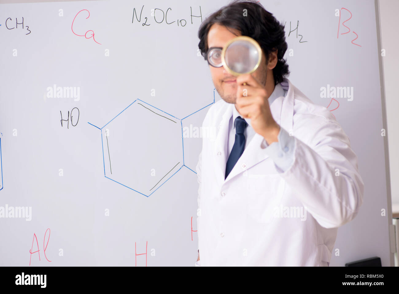 Young funny chemist in front of white board Stock Photo - Alamy