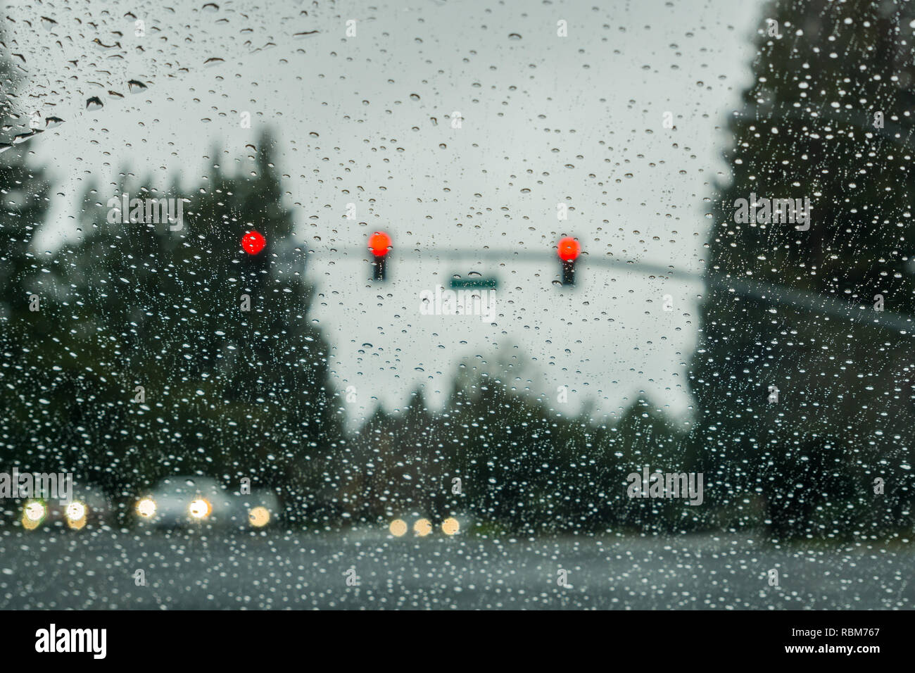 Raindrops on the windshield on a rainy day, traffic light background ...