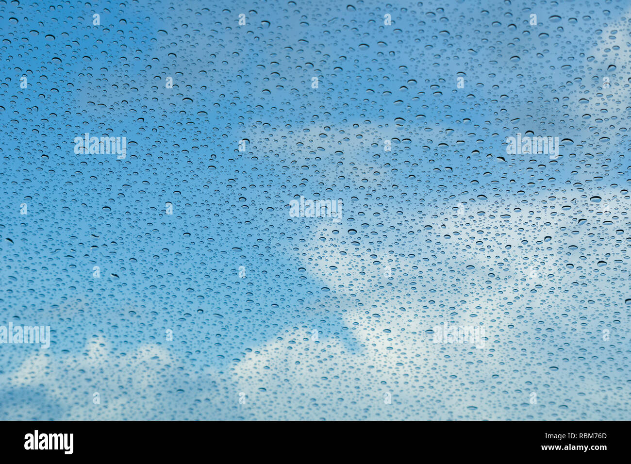 Raindrops on the windshield; in the background blue sky and white ...