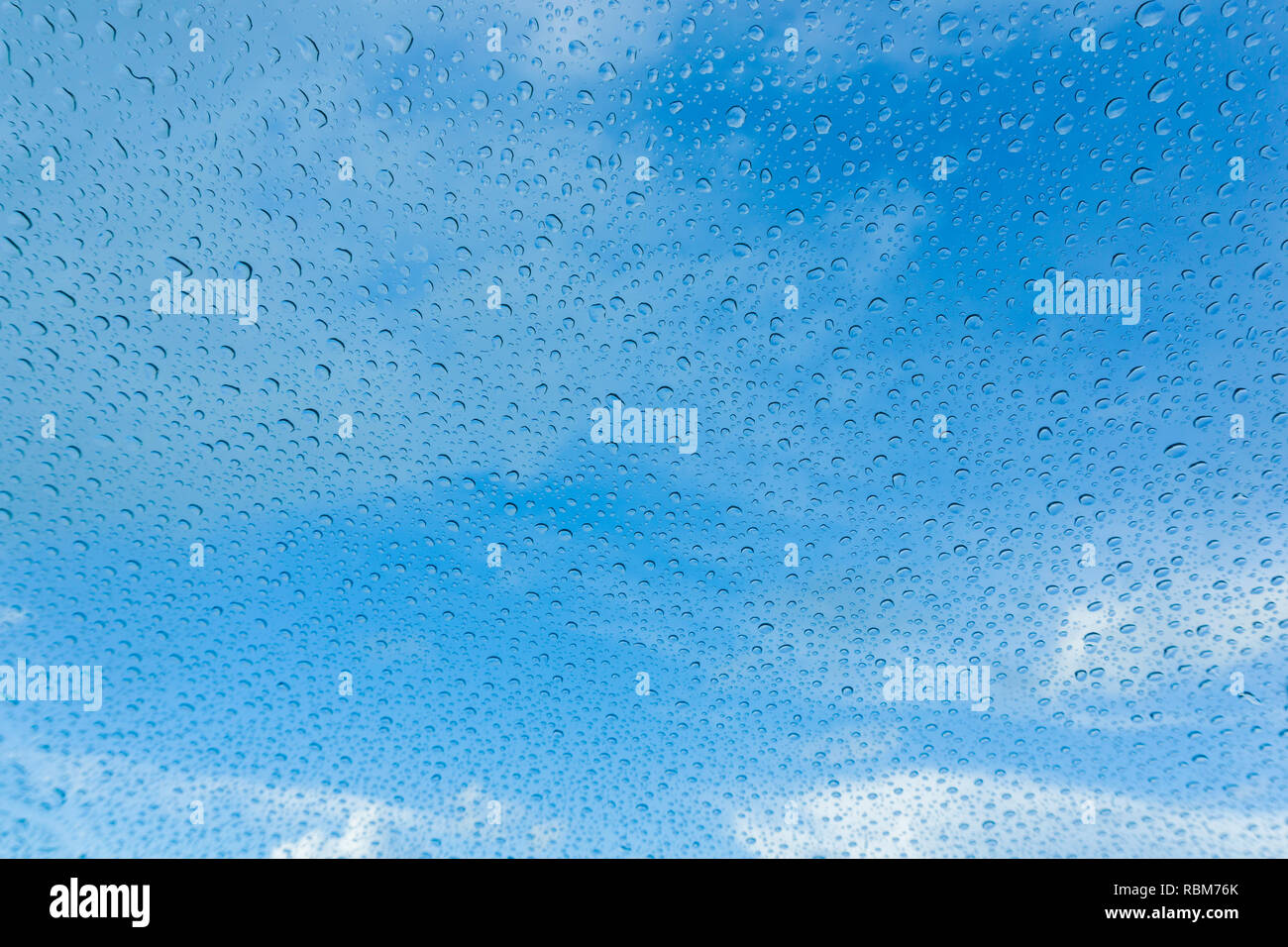 Raindrops on the windshield; in the background blue sky and white ...
