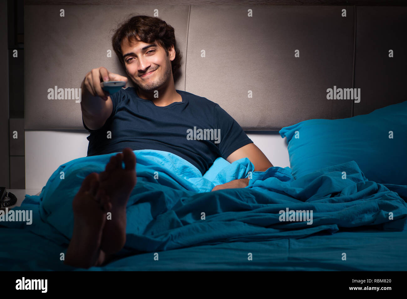 Man watching tv at night in bed Stock Photo - Alamy