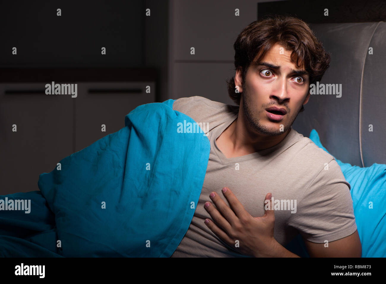 Young man scared in his bed having nightmares Stock Photo - Alamy