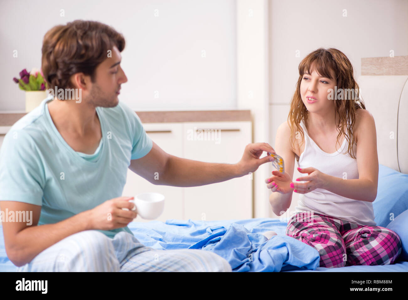 Young husband looking after sick wife in the bedroom Stock Photo - Alamy
