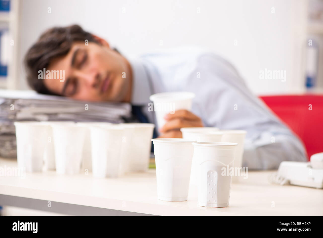 Young employee addicted to coffee Stock Photo - Alamy