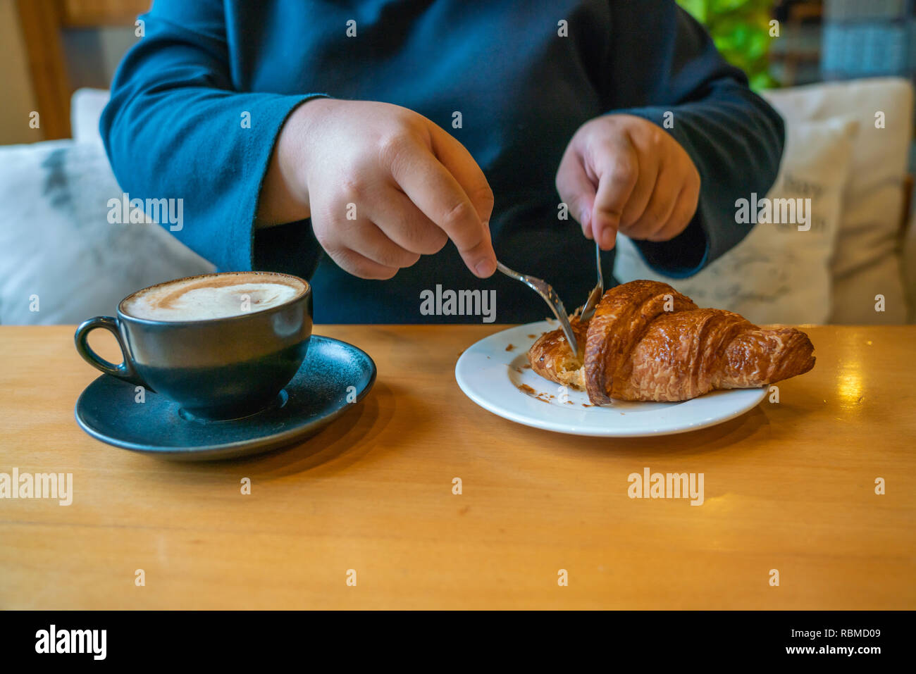 Woman eating croissant with fork and knife Stock Photo - Alamy