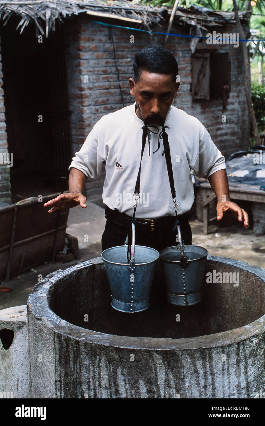 Sailendra Nath Roy holding buckets of water with his moustache, India ...