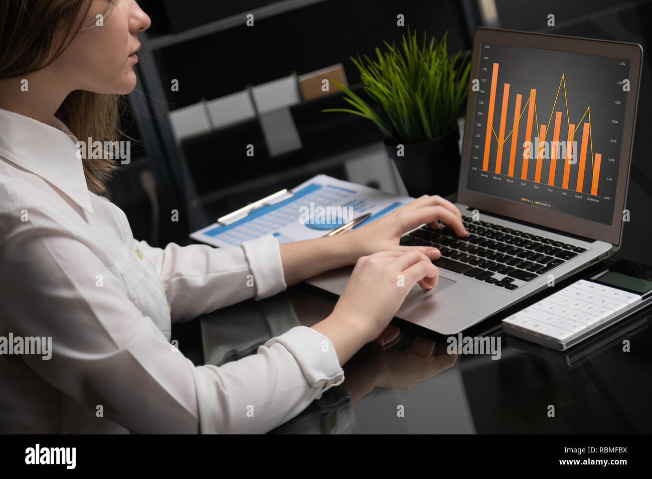 Freelancer typing on laptop with blank black screen next charts and ...