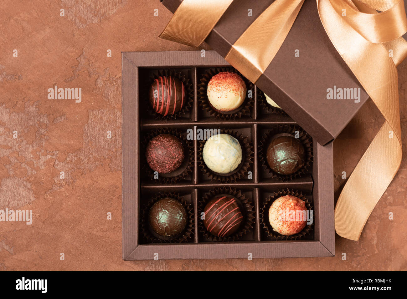 Fine chocolates in craft box with satin ribbon on a dark background ...