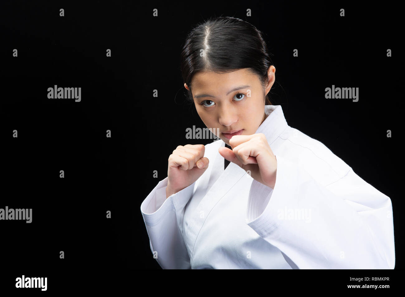 Young beautiful woman wearing a karate suit performing Karate on black ...