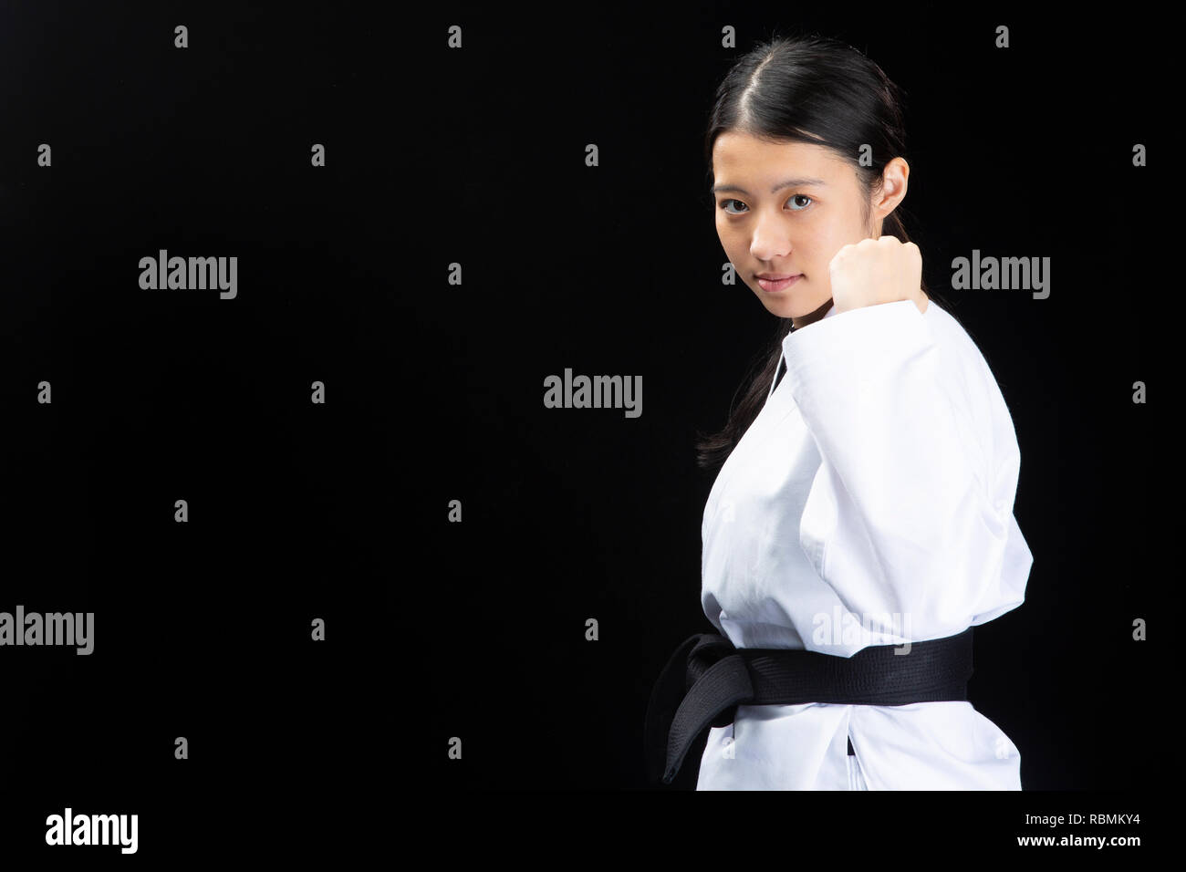 Young beautiful woman wearing a karate suit performing Karate on black ...