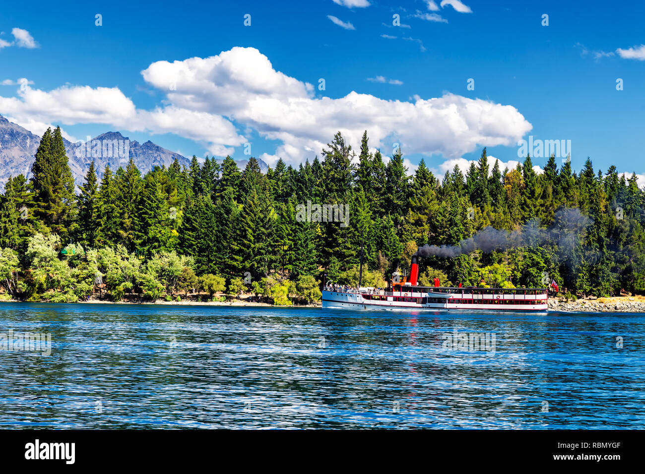 Steam-powered ship on lake Wakatipu surrounded by coniferous forest in ...
