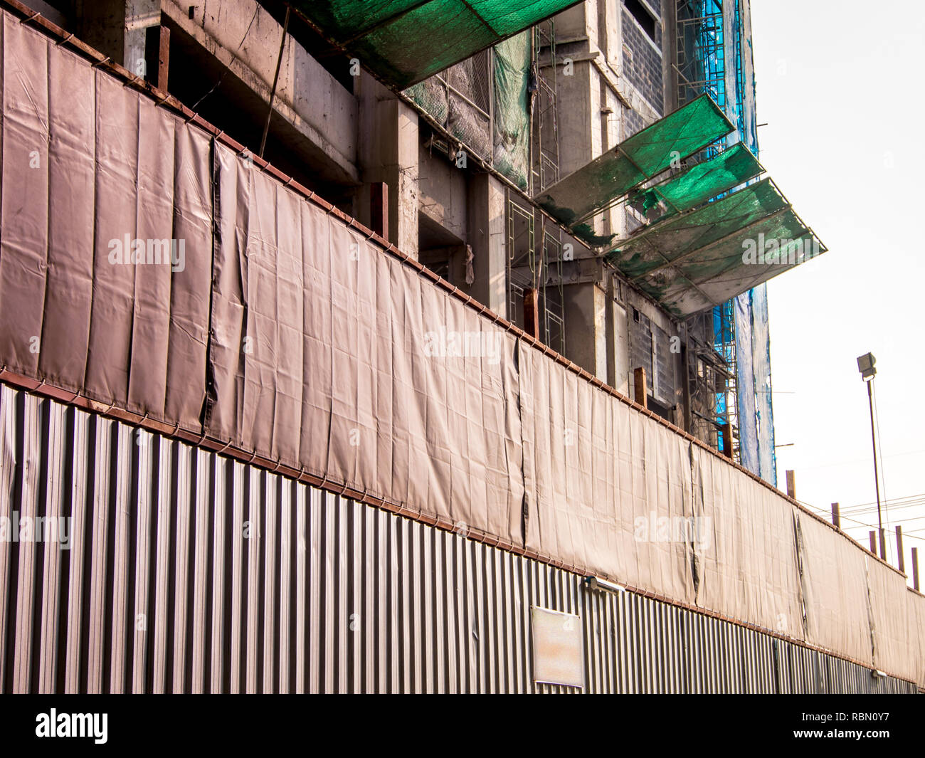 The high-rise building under construction behind the fence Stock Photo ...