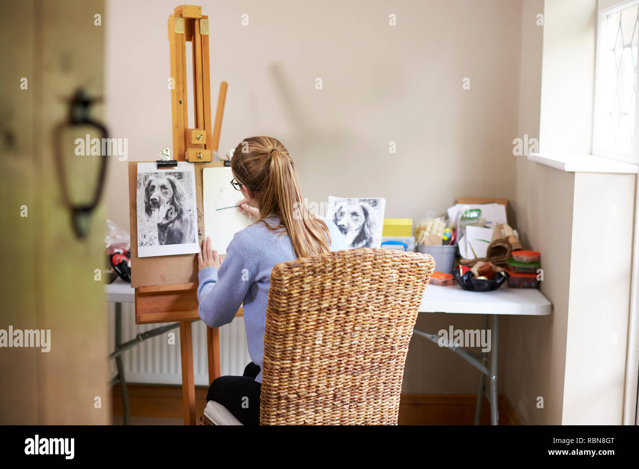 Female Teenage Artist Sitting At Easel Drawing Picture Of Dog From ...